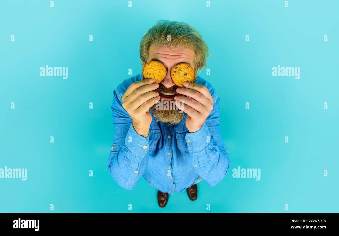 Sweet snack. Bearded man covered eyes with delicious oatmeal cookies ...