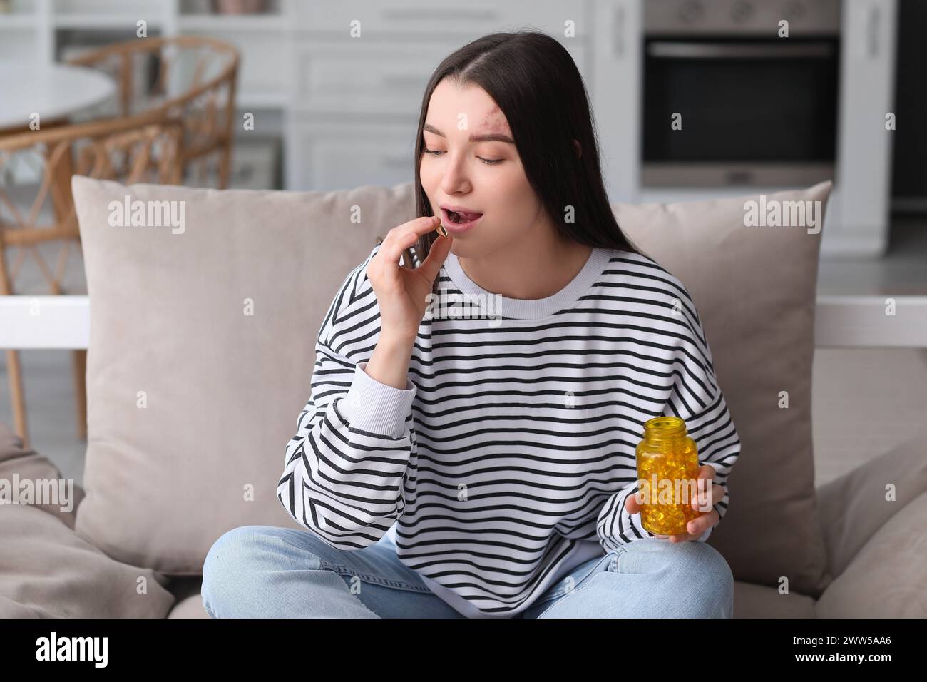 Young woman taking vitamin supplement at home Stock Photo - Alamy