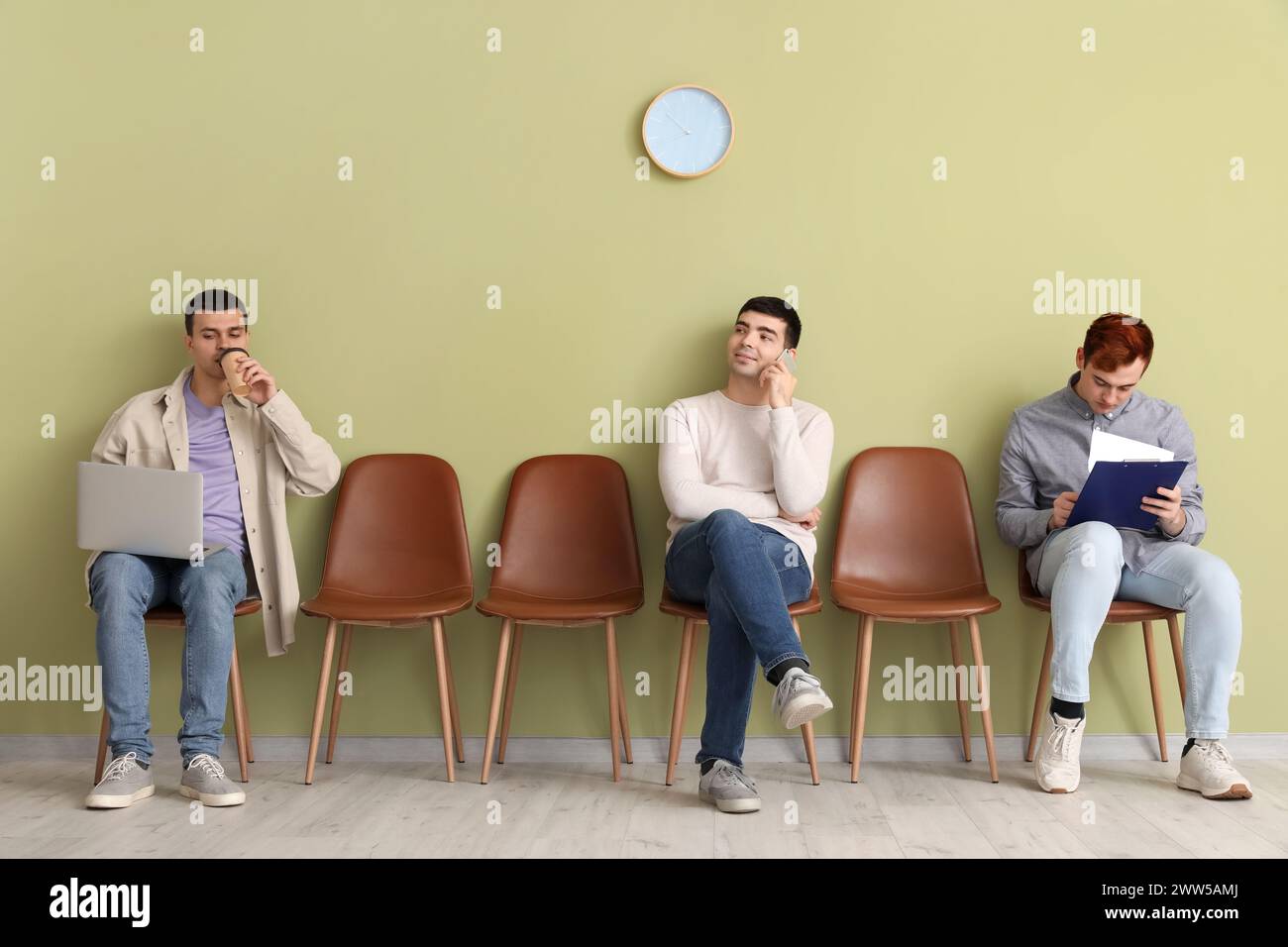 Male applicants waiting for job interview near green wall in room Stock ...