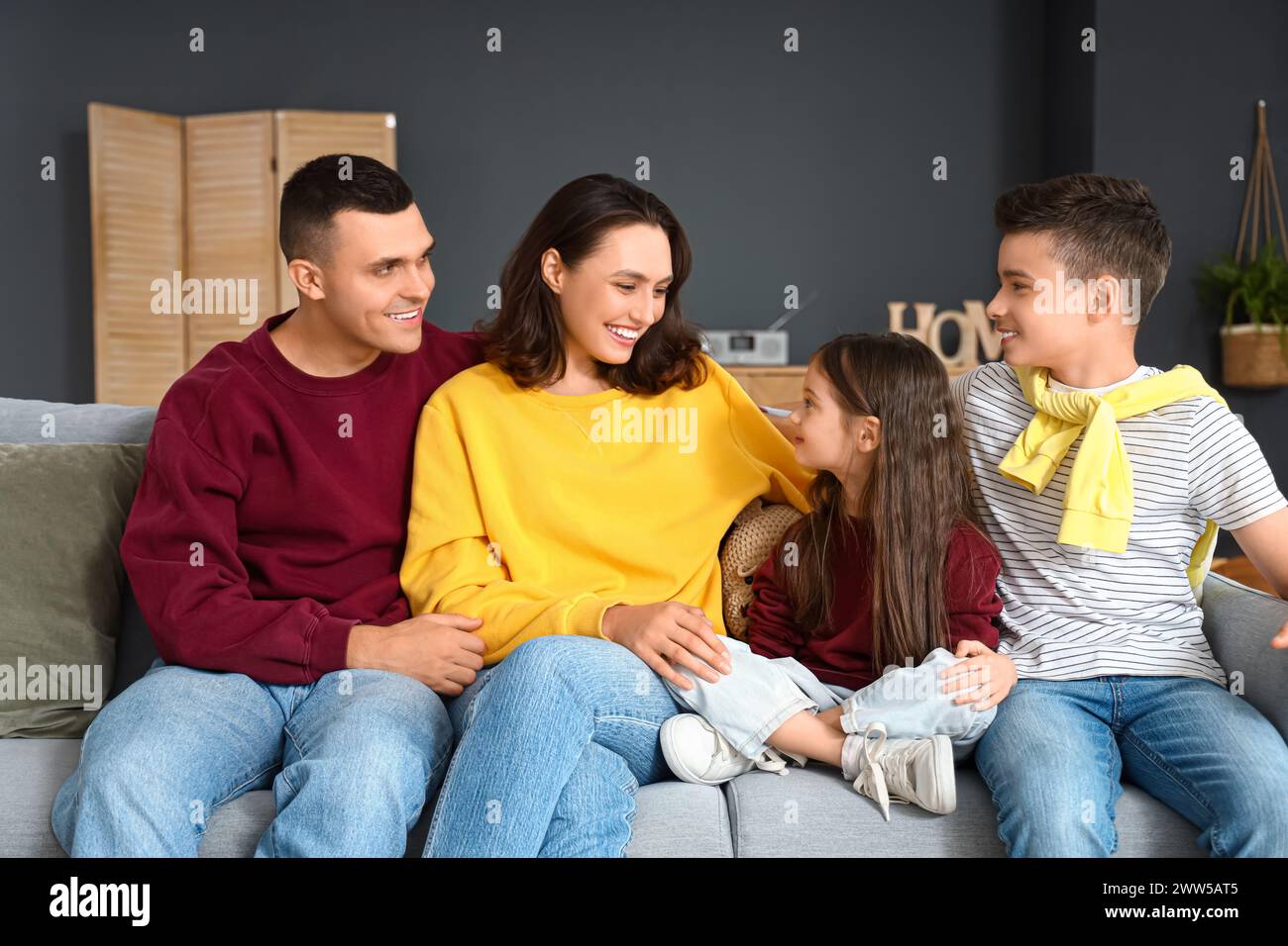 Little children with their parents sitting on sofa at home Stock Photo ...