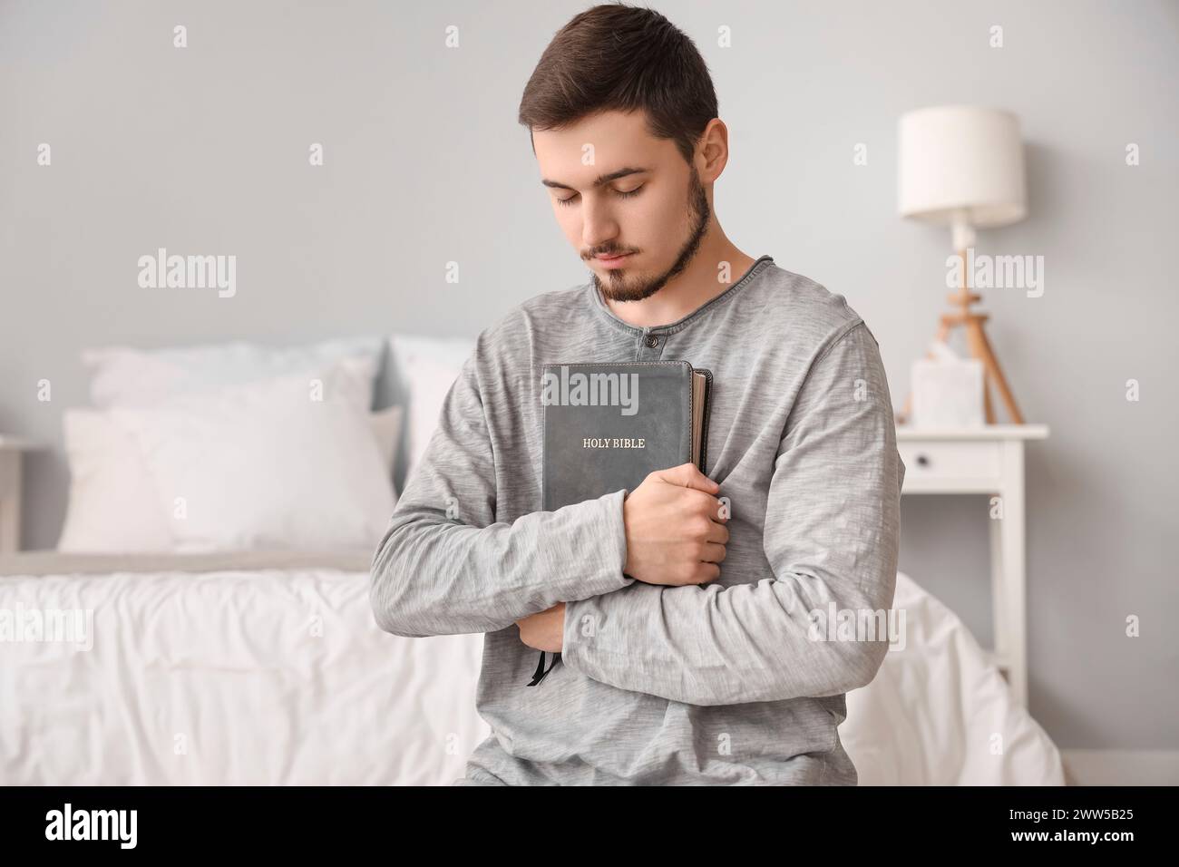 Young man with Bible praying in bedroom Stock Photo - Alamy