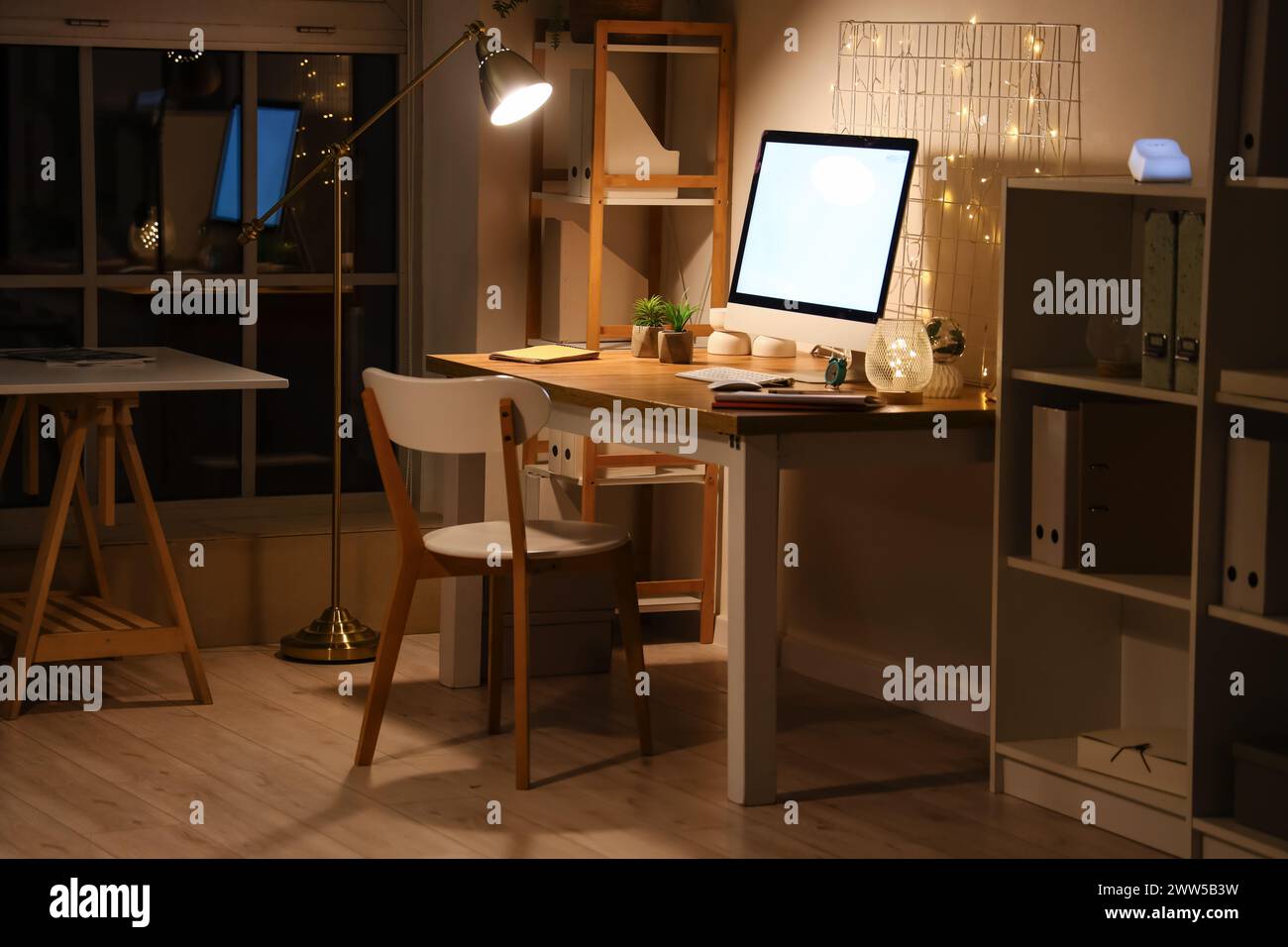 Interior of office with workplace, blank computer and glowing lights ...