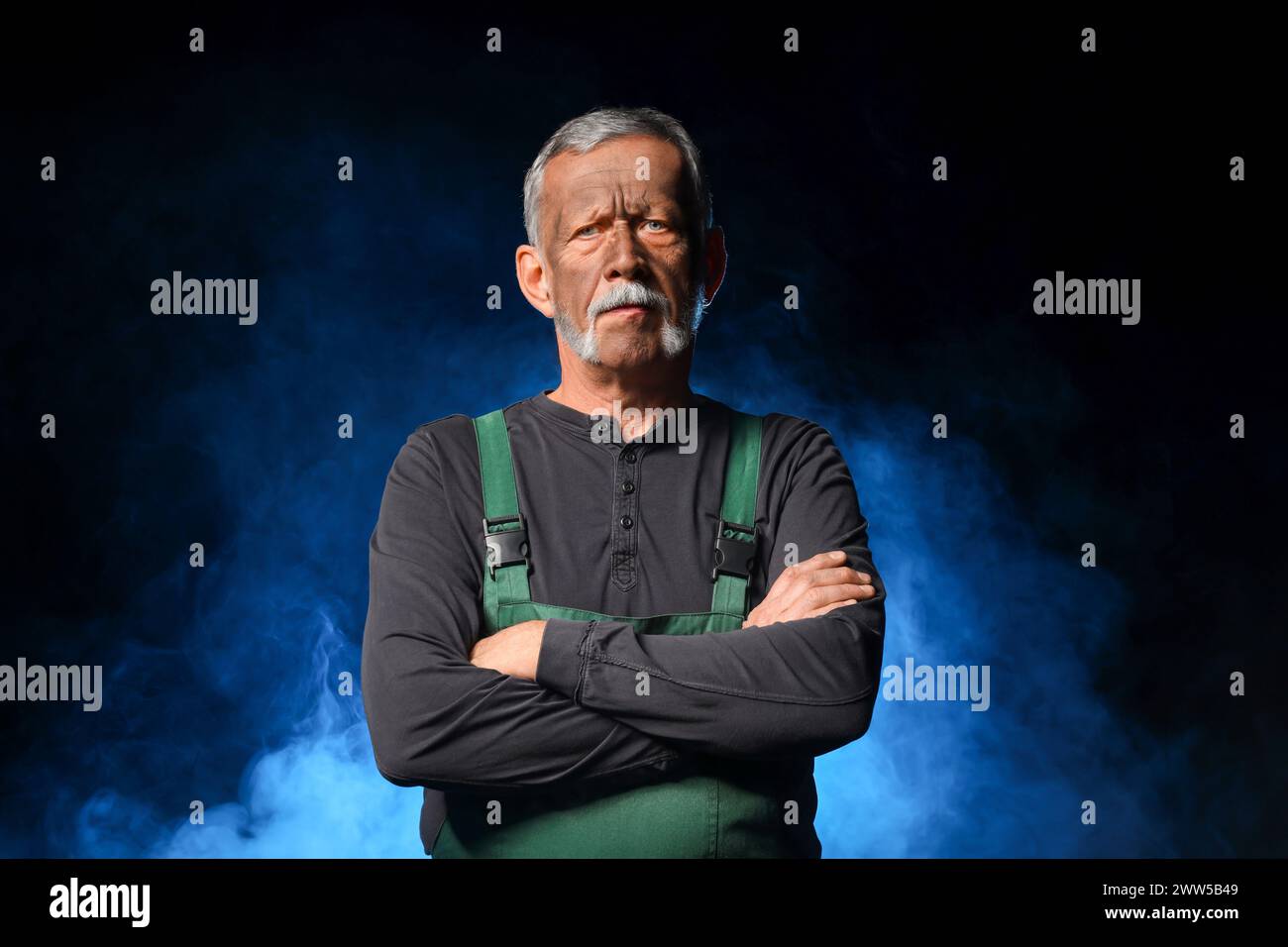 Mature miner man and blue smoke on black background Stock Photo - Alamy