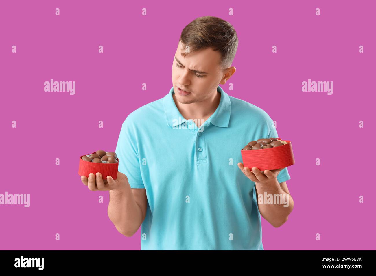 Thoughtful young man with boxes of heart-shaped chocolate candies on ...