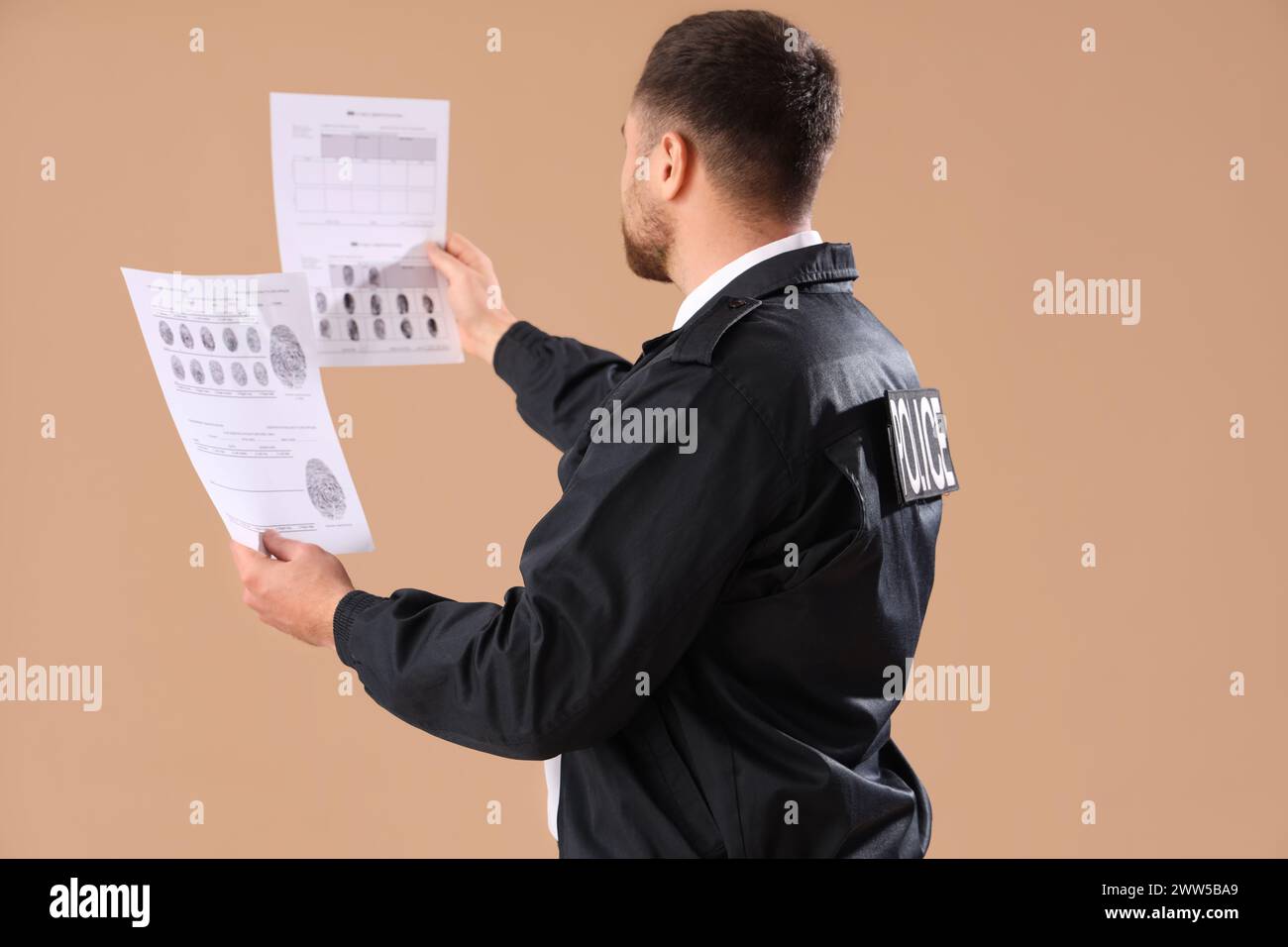 Male police officer with documents on beige background Stock Photo - Alamy
