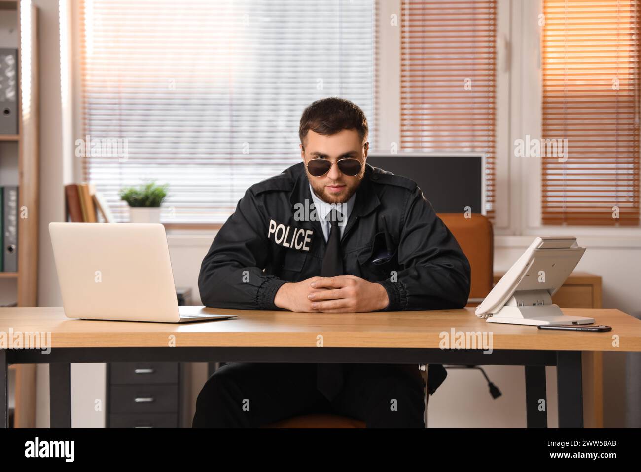 Male police officer sitting in office Stock Photo - Alamy