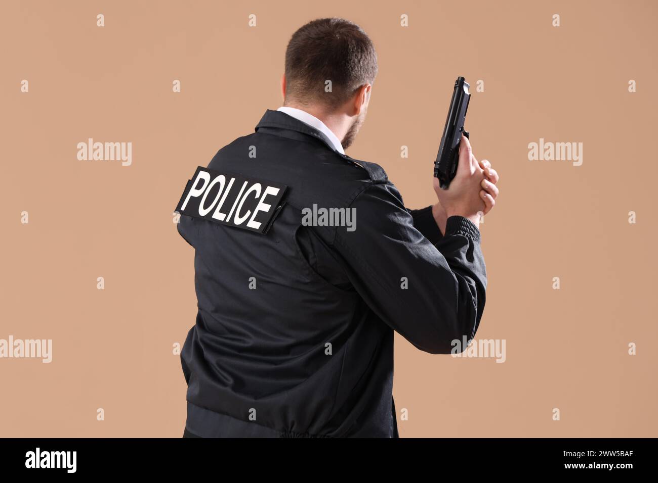 Male police officer with gun on beige background Stock Photo - Alamy