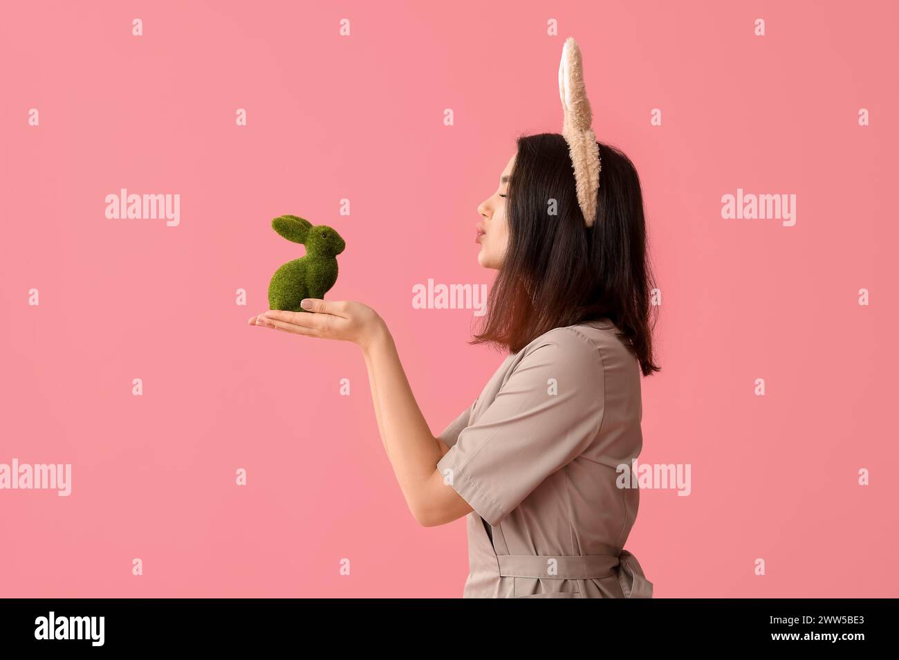 Female massage therapist in bunny ears with Easter rabbit blowing kiss ...