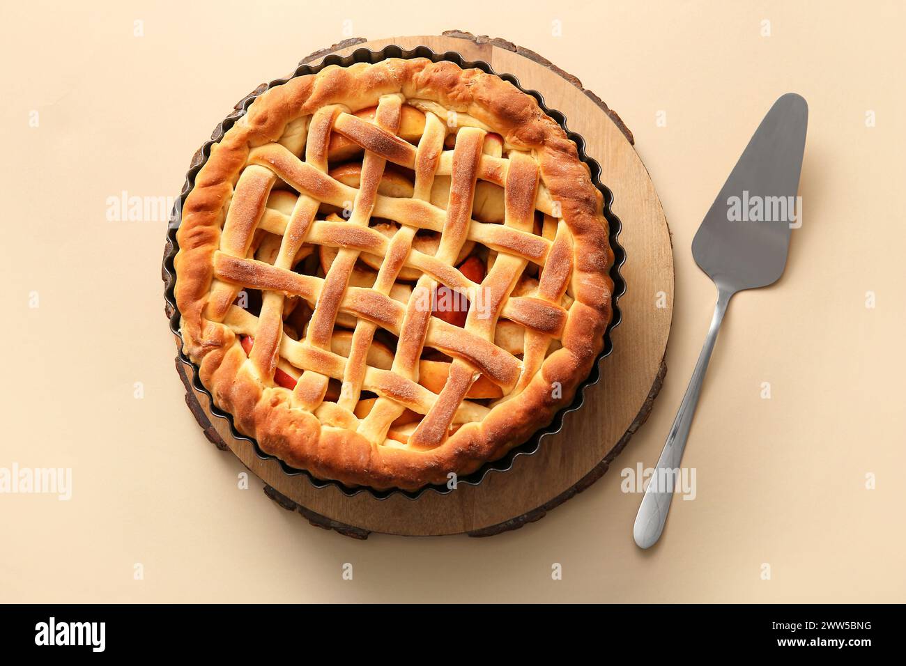 Wooden tray with tasty homemade apple pie and spatula on beige ...