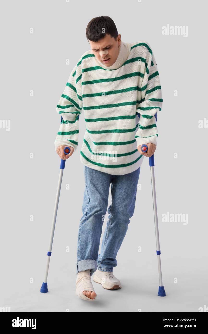 Injured young man after accident with crutches walking on light ...