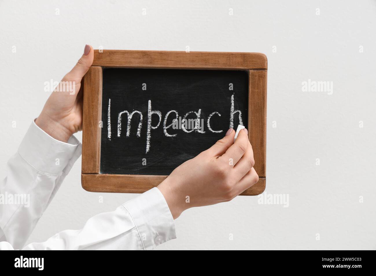 Woman writing word IMPEACH on chalkboard against white background Stock ...