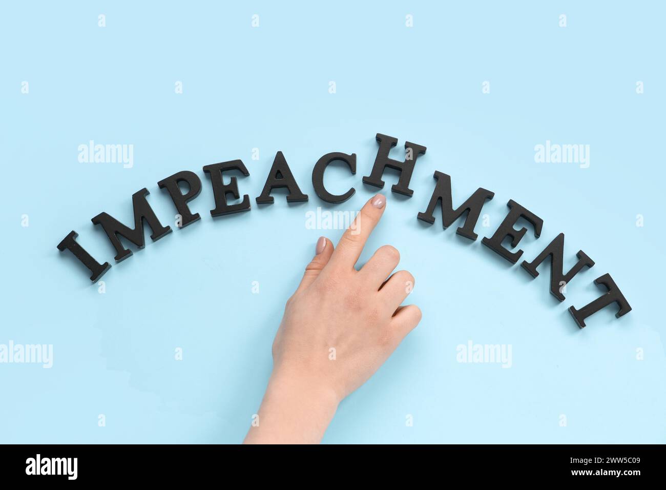 Female hand with black letters spelling word IMPEACHMENT on blue ...