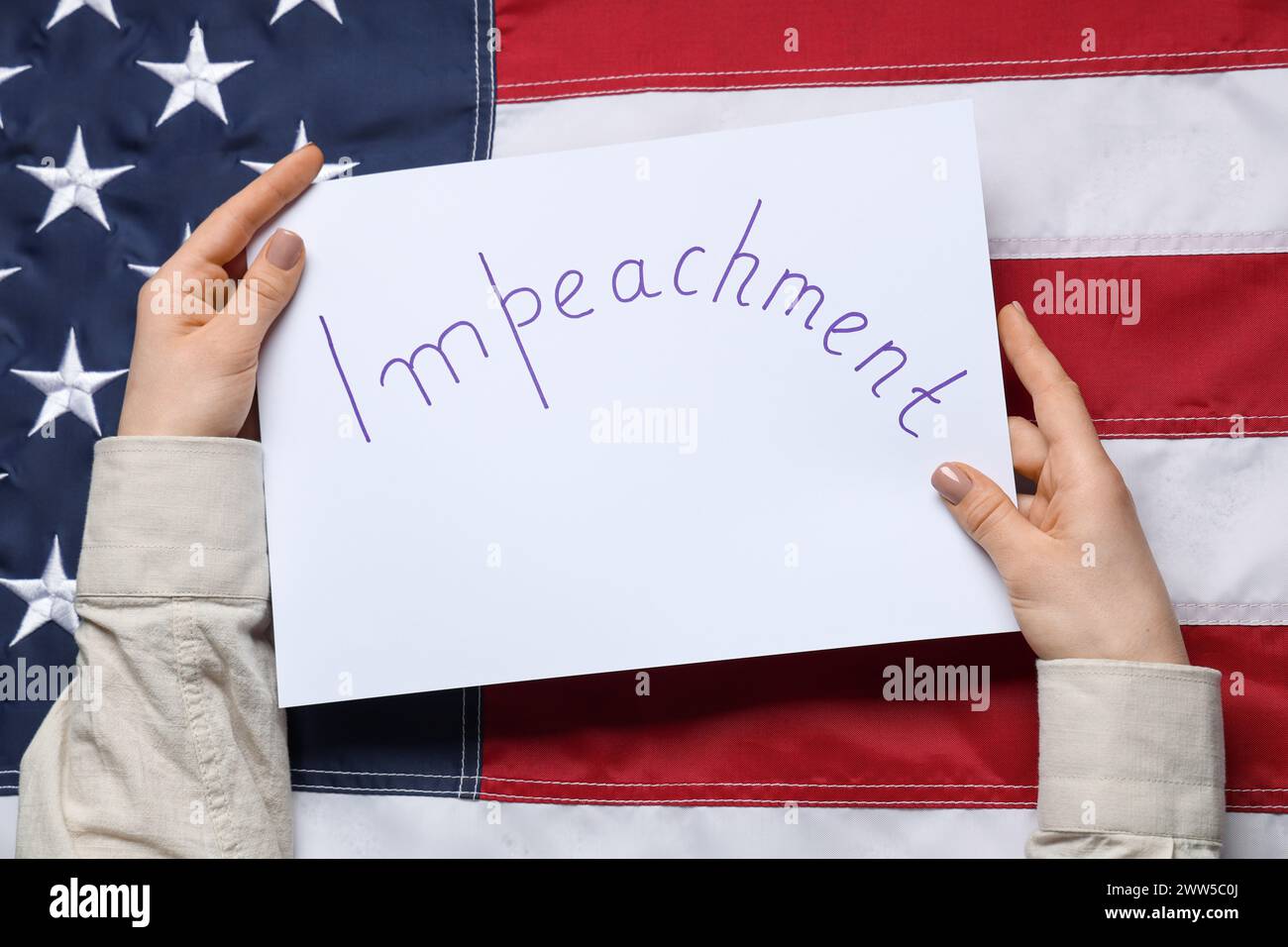 Woman holding IMPEACHMENT picket poster against USA flag background ...