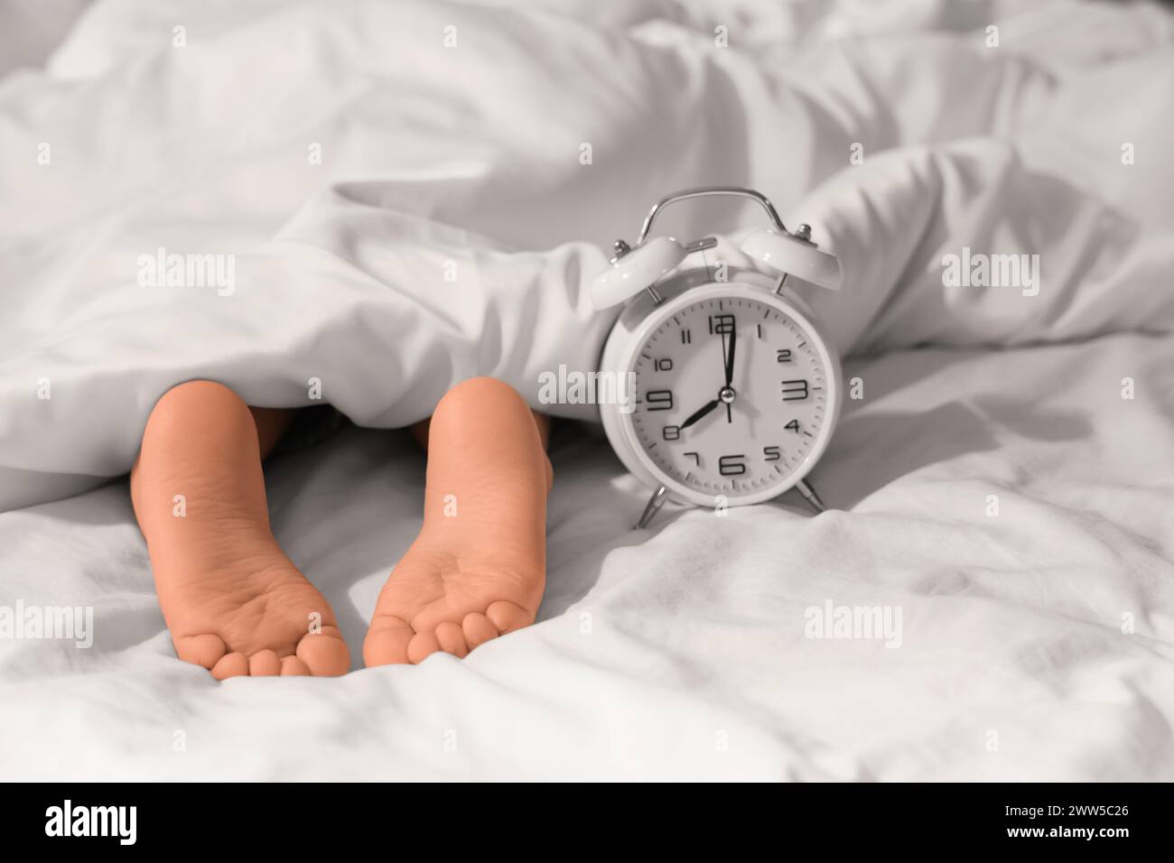 Alarm clock and feet of little girl under blank on bed Stock Photo - Alamy