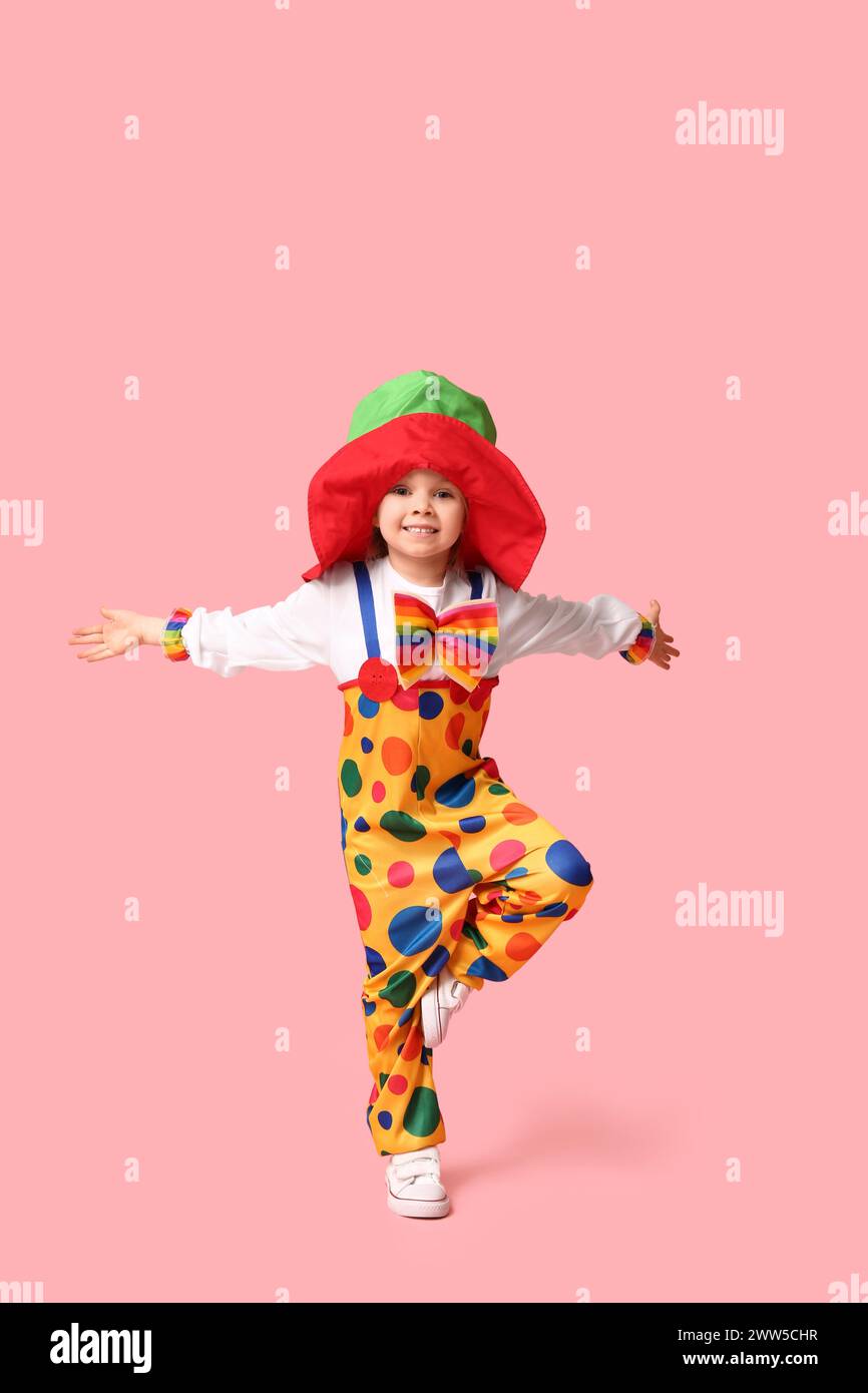 Funny little girl in clown costume with hat on pink background Stock ...