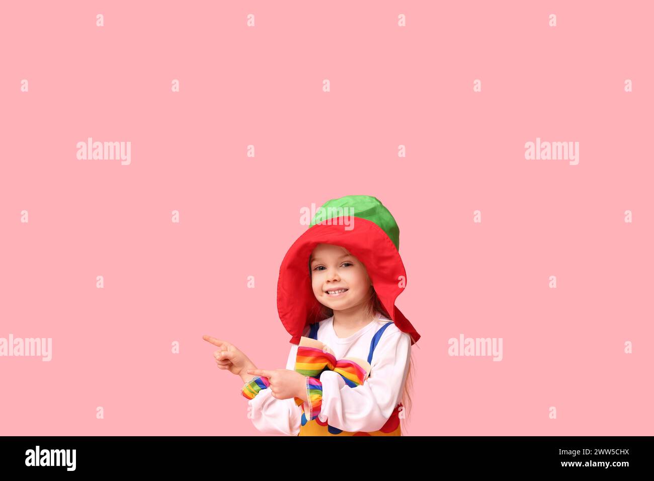 Little girl in clown costume and hat on pink background Stock Photo - Alamy