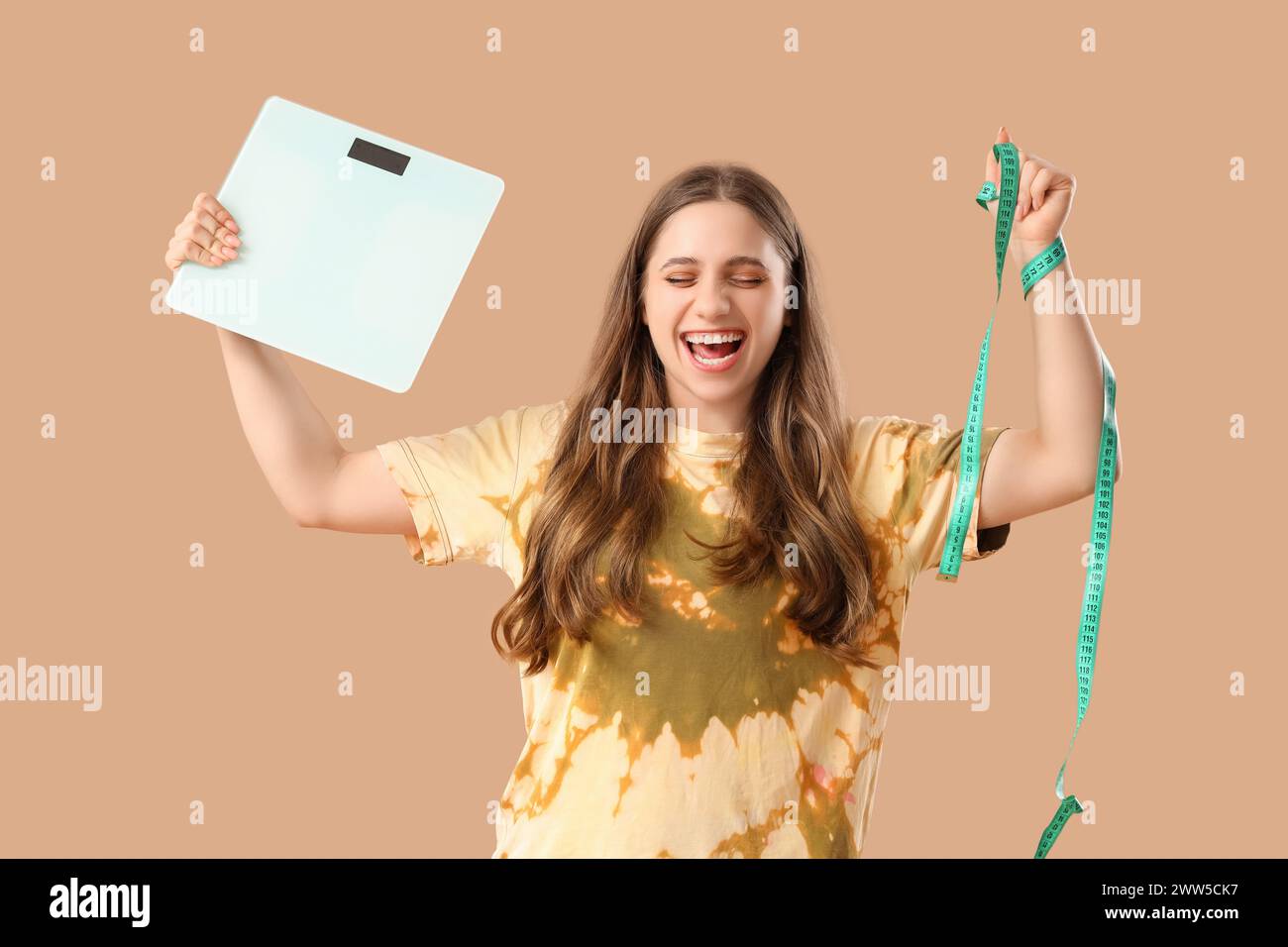 Pretty young woman in sportswear with scales and measuring tape ...