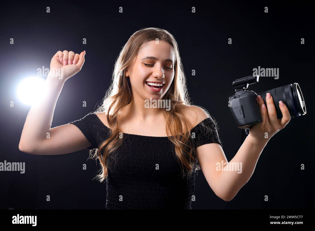 Portrait of happy female photographer with modern camera and spotlight ...