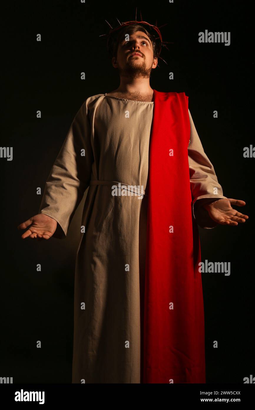 Man in Jesus robe and crown of thorns outstretching hands with light on ...