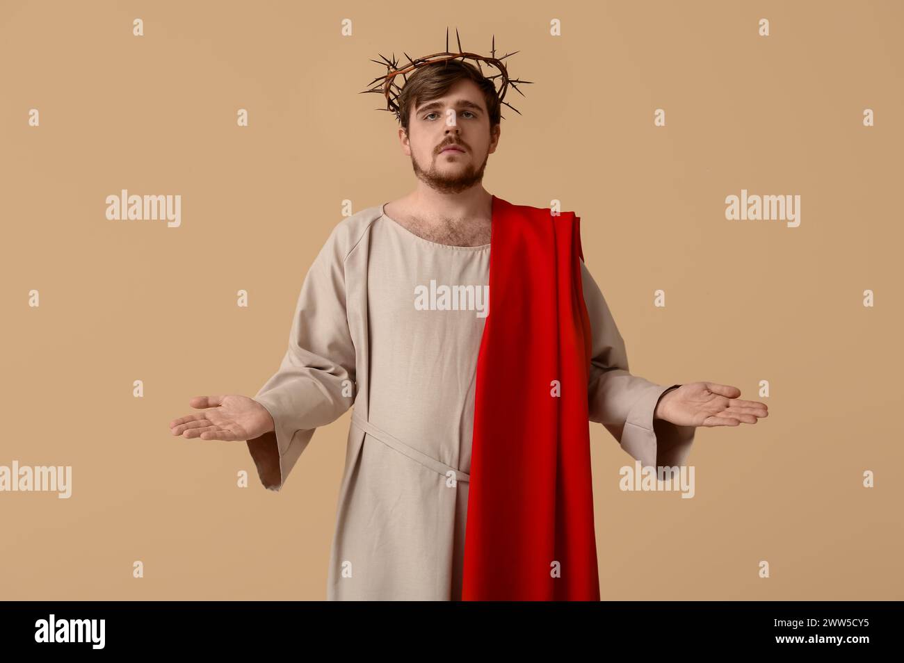 Man in Jesus robe and crown of thorns with outstretched hands on beige ...