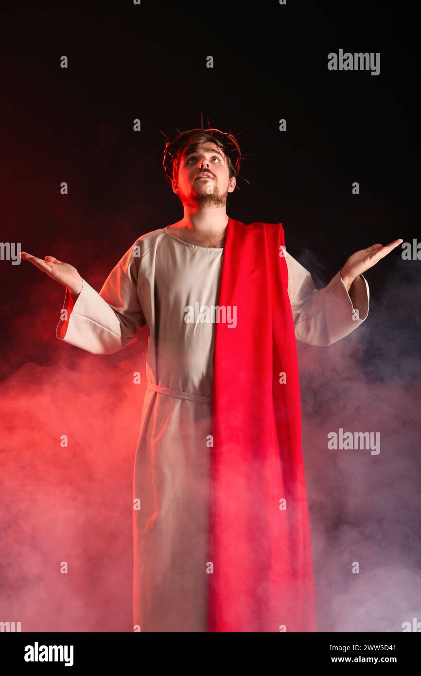 Man in Jesus robe and crown of thorns outstretching hands with smoke on ...