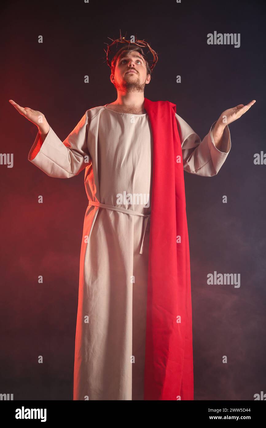 Man in Jesus robe and crown of thorns outstretching hands with smoke on ...