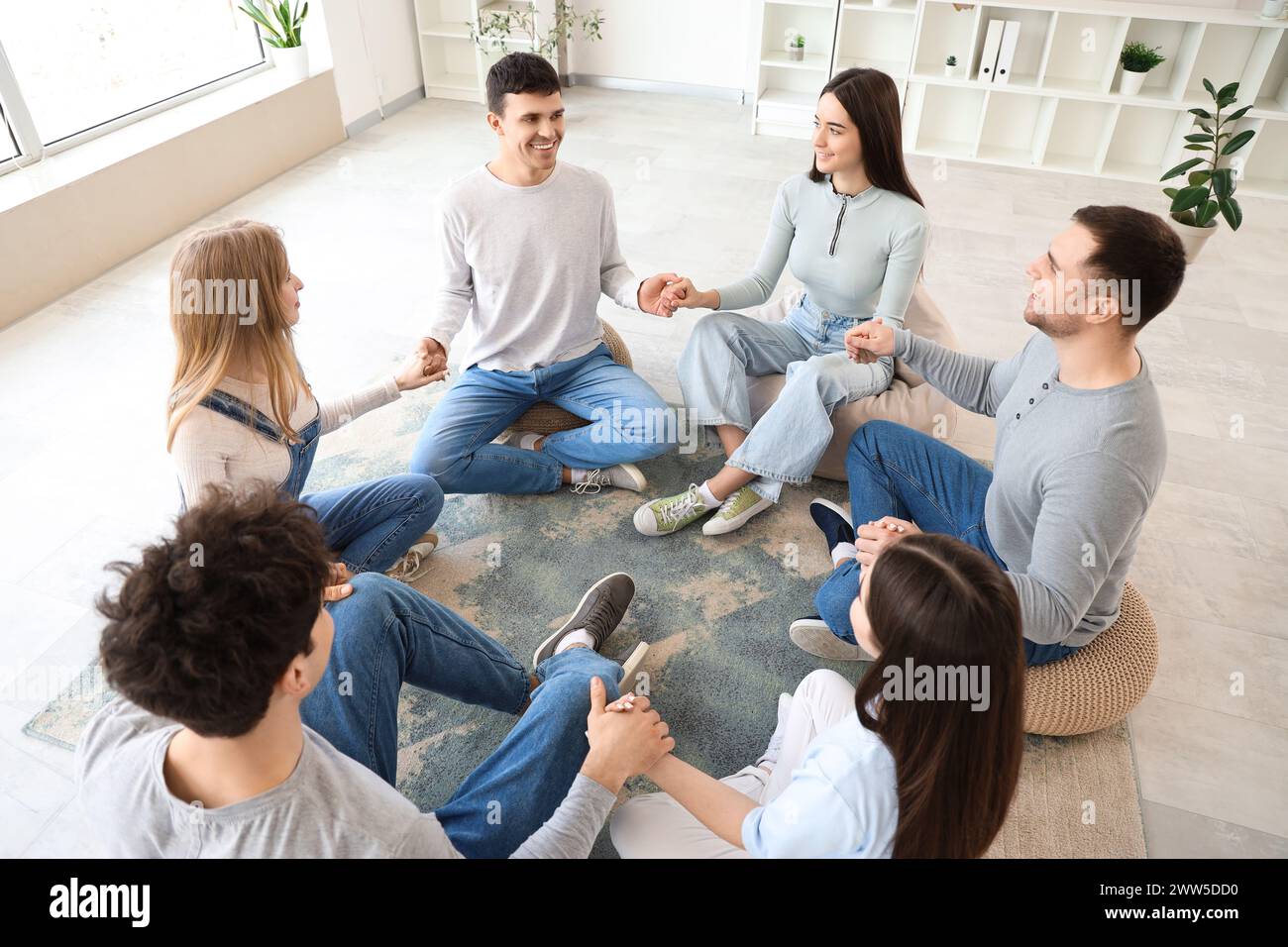 Young people holding hands at group therapy session Stock Photo - Alamy