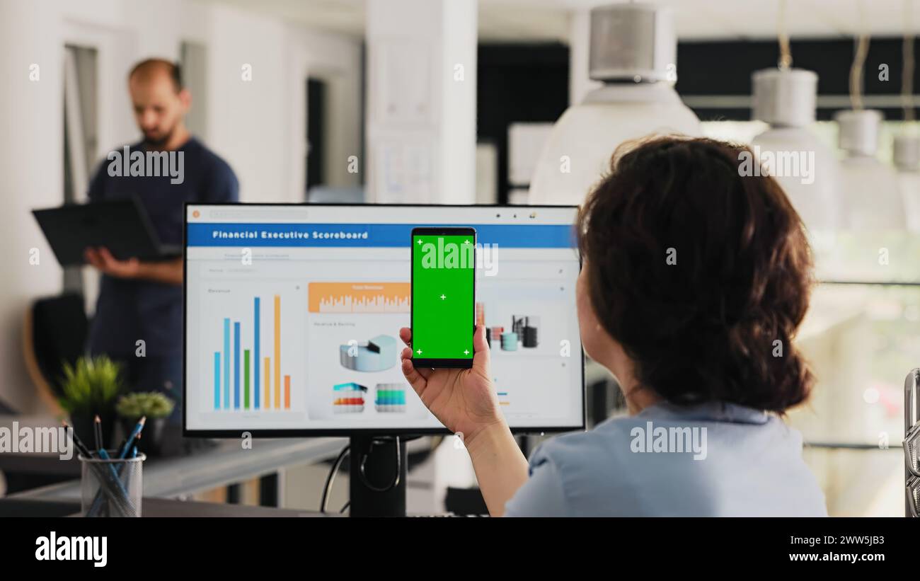 Employee uses phone app with greenscreen sitting at desk in creative ...