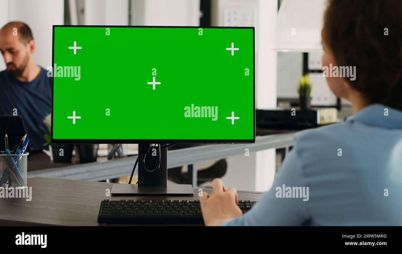 Manager working with isolated greenscreen on computer at workstation ...