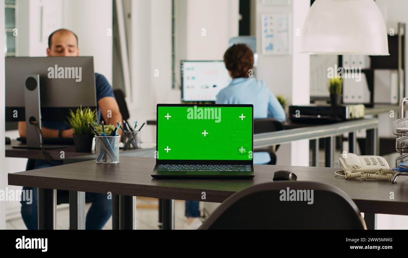 Laptop with greenscreen display on desk in modern startup agency office ...