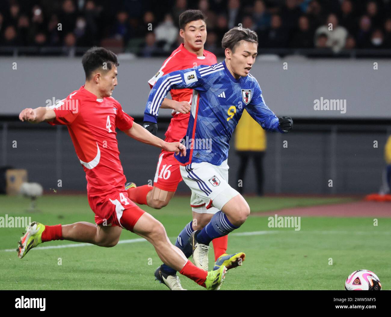 Tokyo, Japan. 21st Mar, 2024. Japan's Ayase Ueda (R) fights the ball ...