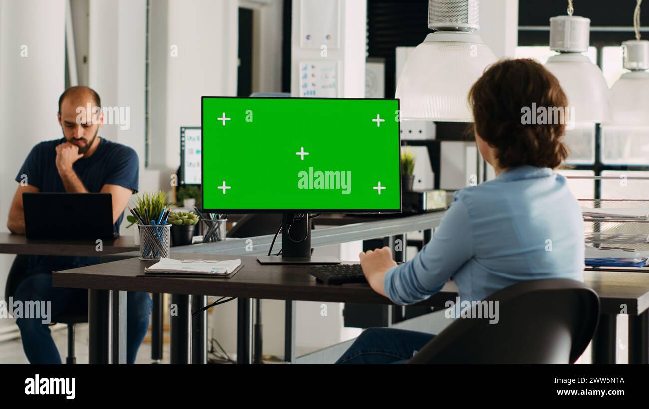 Businesswoman looking at greenscreen display to work on agency tasks ...