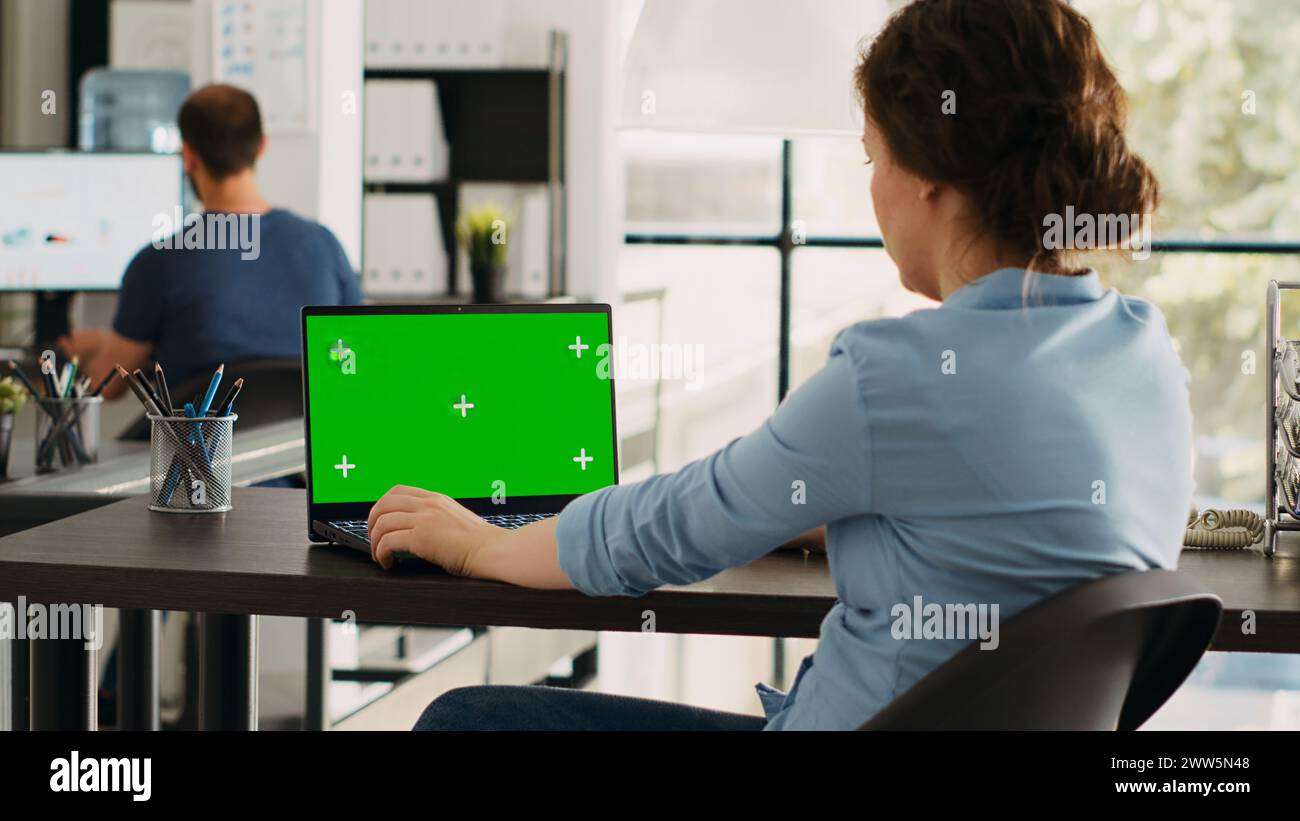 Businesswoman looks at greenscreen on laptop, checking pc at desk and ...