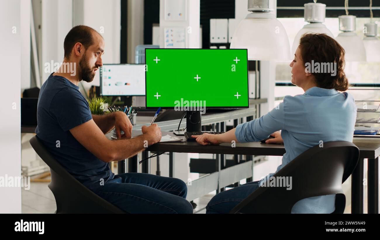 Startup team looking at pc with greenscreen, small business office desk. Company workers ...