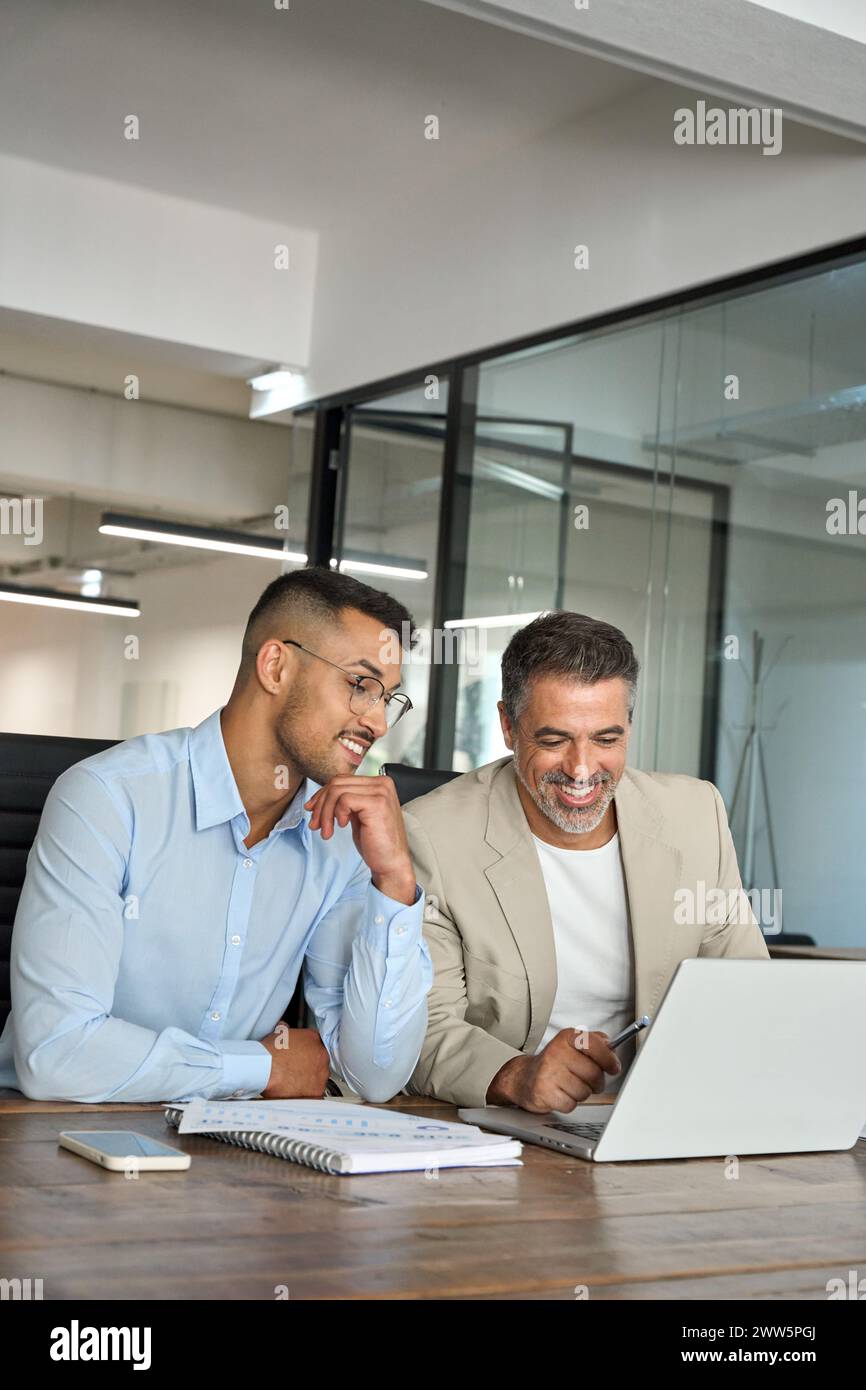 Two busy happy business men working together using laptop in office ...