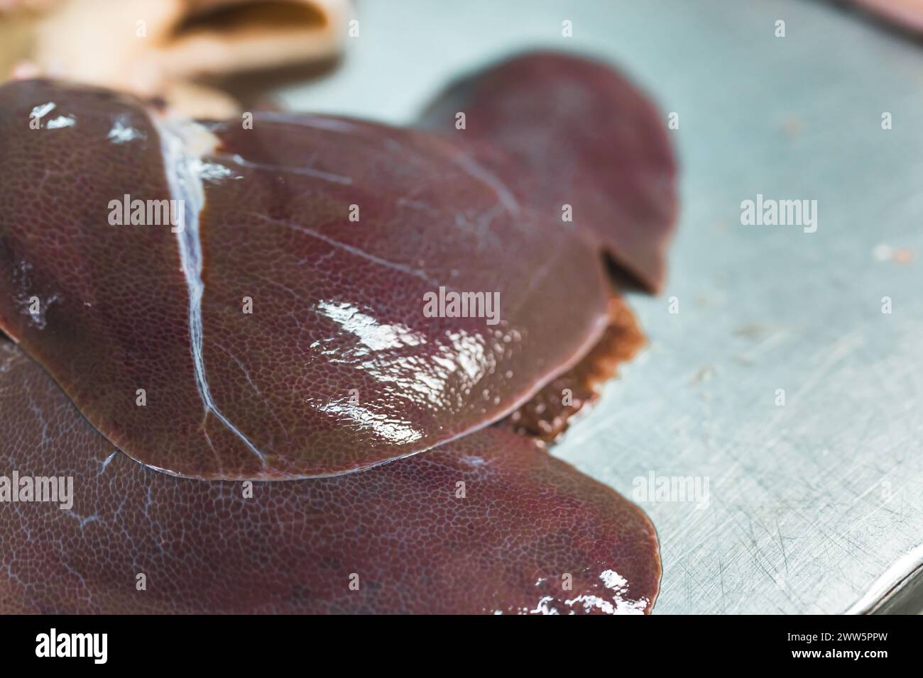 cutting pig liver at the slaughterhouse, pig meat processing. High ...