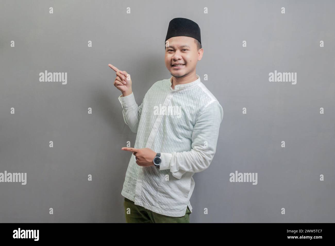 Happy asian muslim man recommend promo as pointing to copy space ...