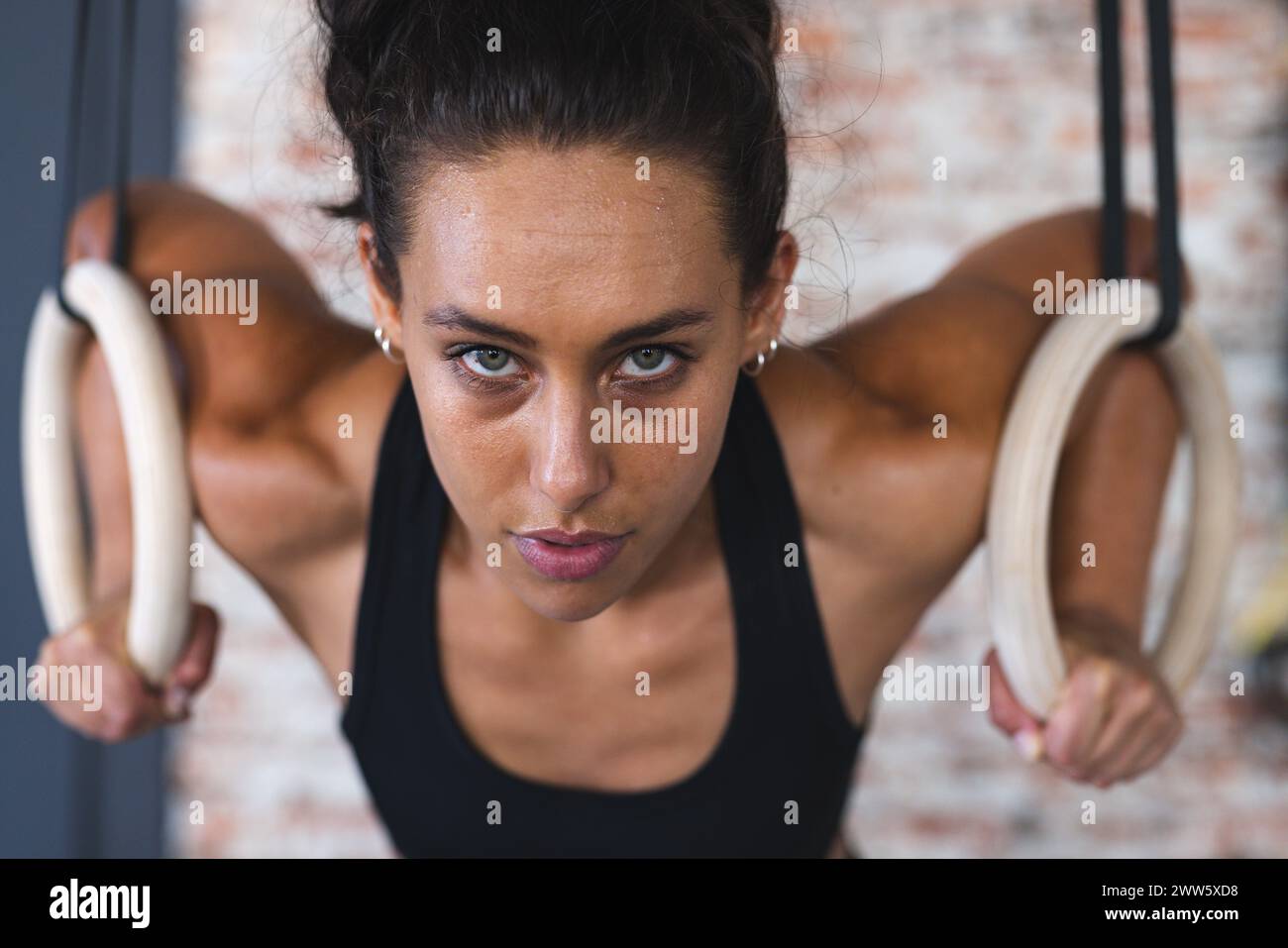 A fit Caucasian woman engages with gymnastic rings in the gym Stock ...