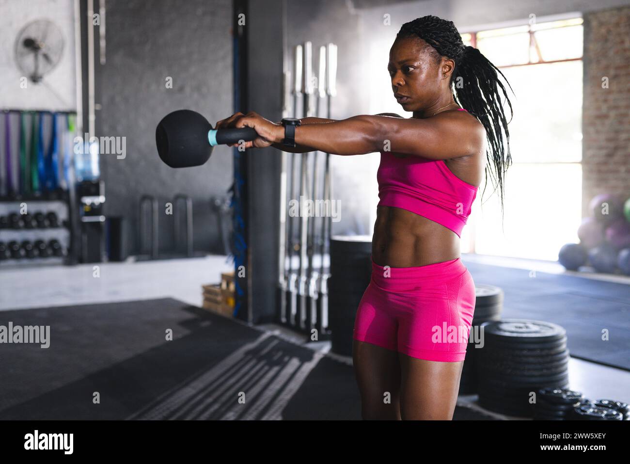 A fit African American strong woman is exercising with a kettlebell in ...
