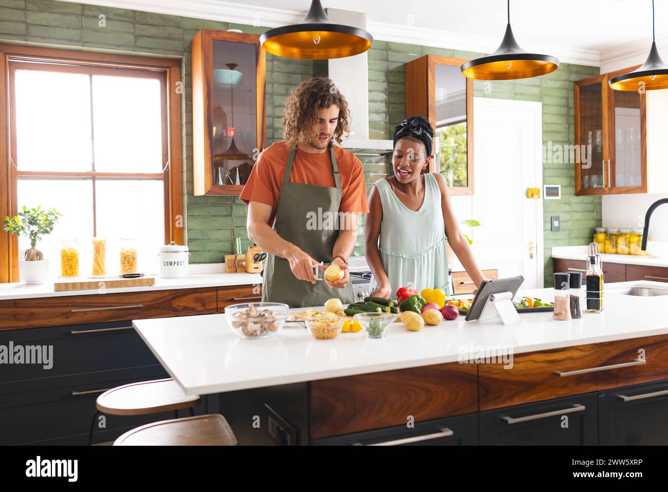 A diverse couple is preparing meal together in a modern kitchen Stock ...