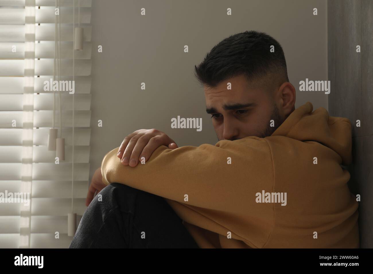 Sad man sitting near window at home Stock Photo - Alamy