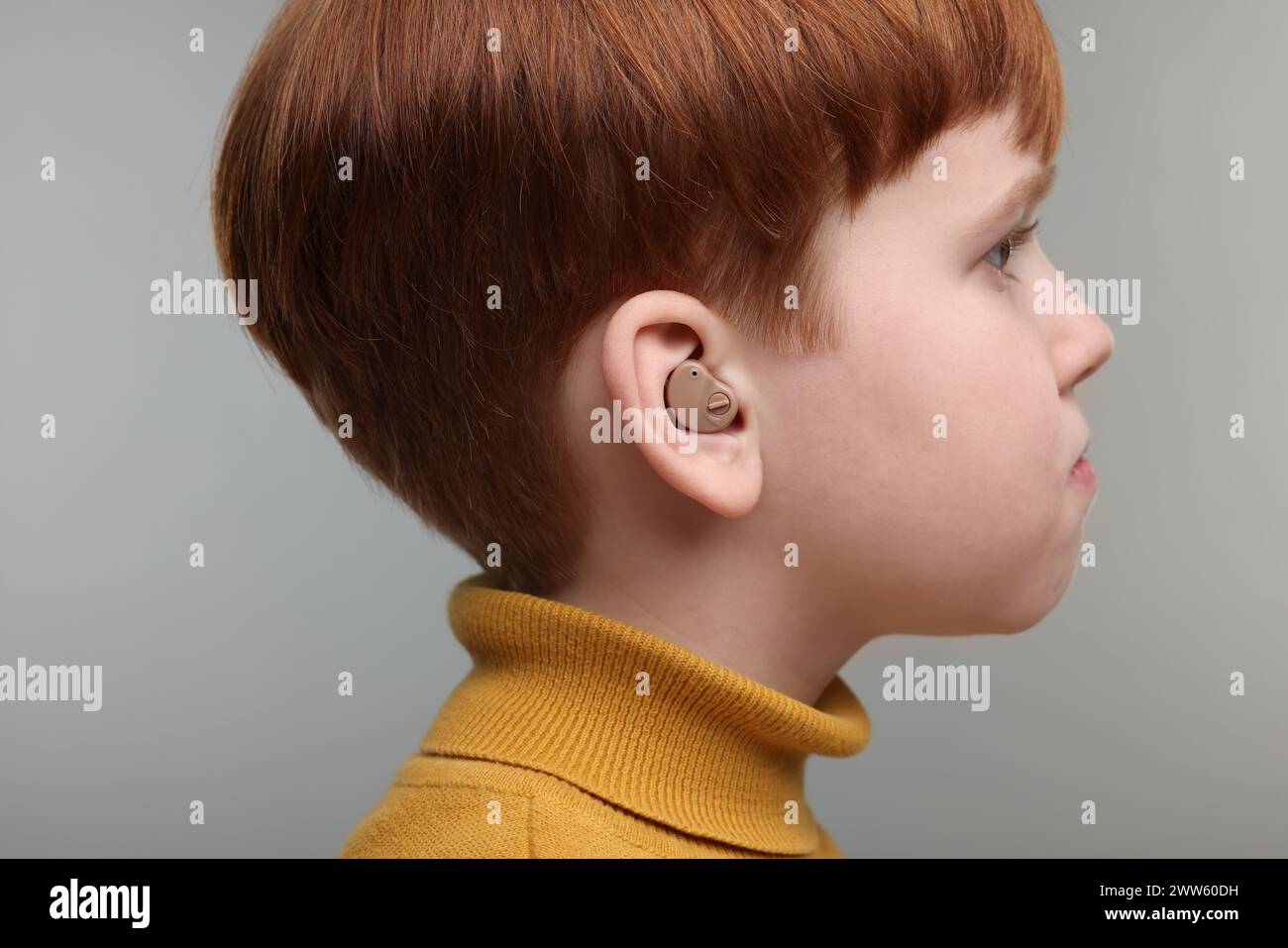 Little boy with hearing aid on grey background, closeup Stock Photo - Alamy