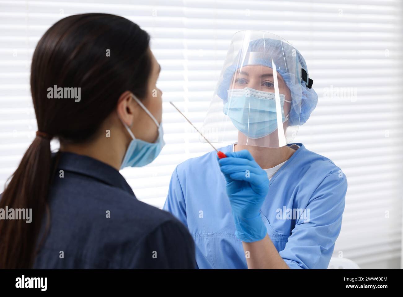 Laboratory testing. Doctor in uniform taking sample from patient's nose ...