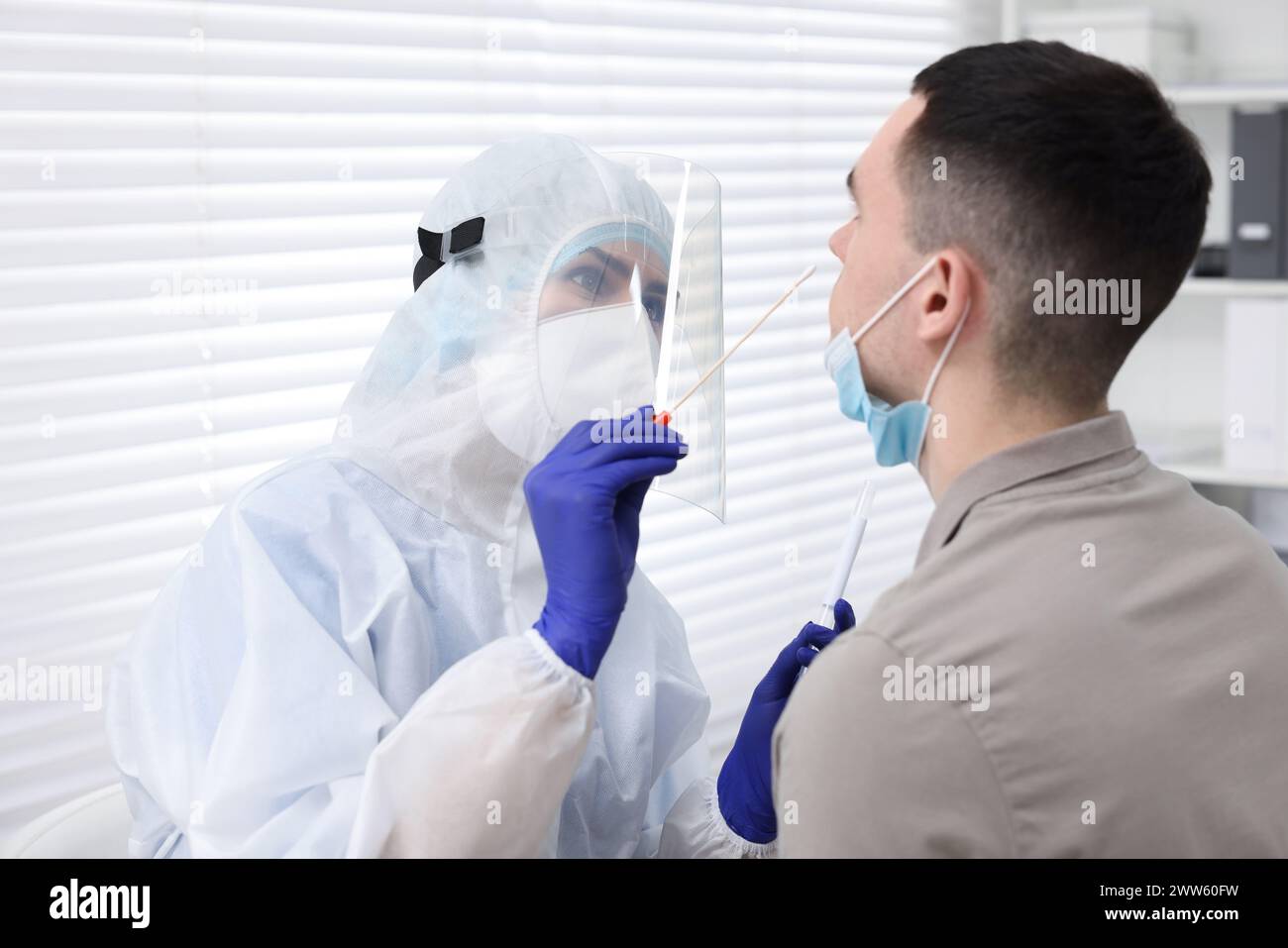 Laboratory testing. Doctor in uniform taking sample from patient's nose ...