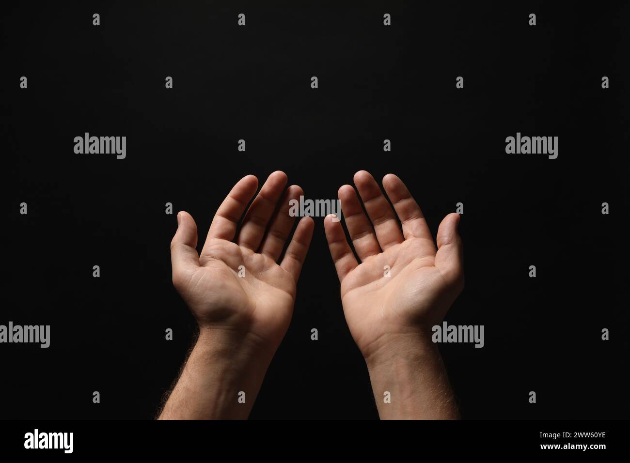 Religion. Man with open palms praying on black background, closeup ...
