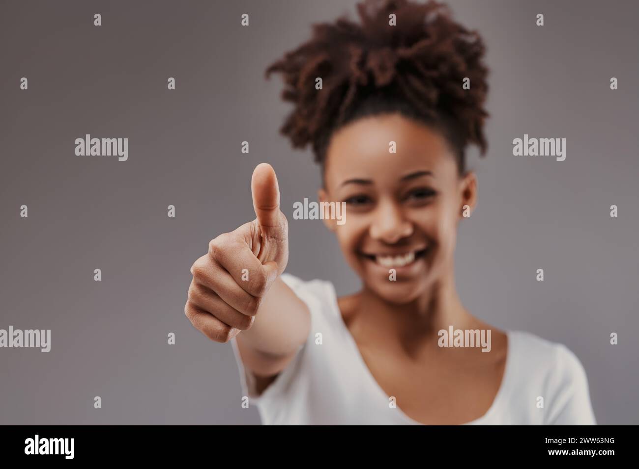 Cheerful and assured, her thumbs-up sign reflects a positive mindset ...