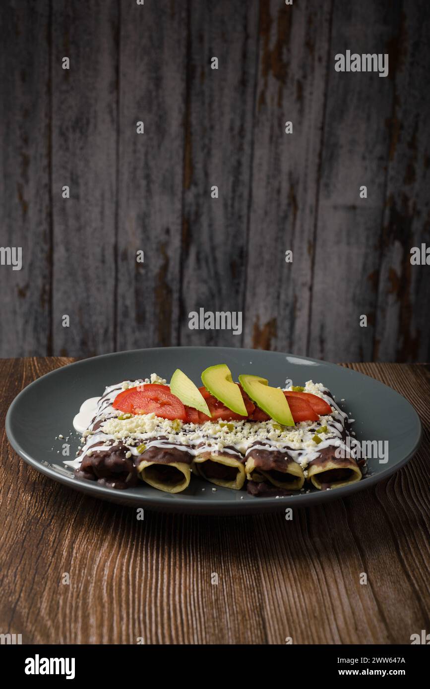 Enfrijoladas served in a clay dish. Typical Mexican food. Bean tacos ...