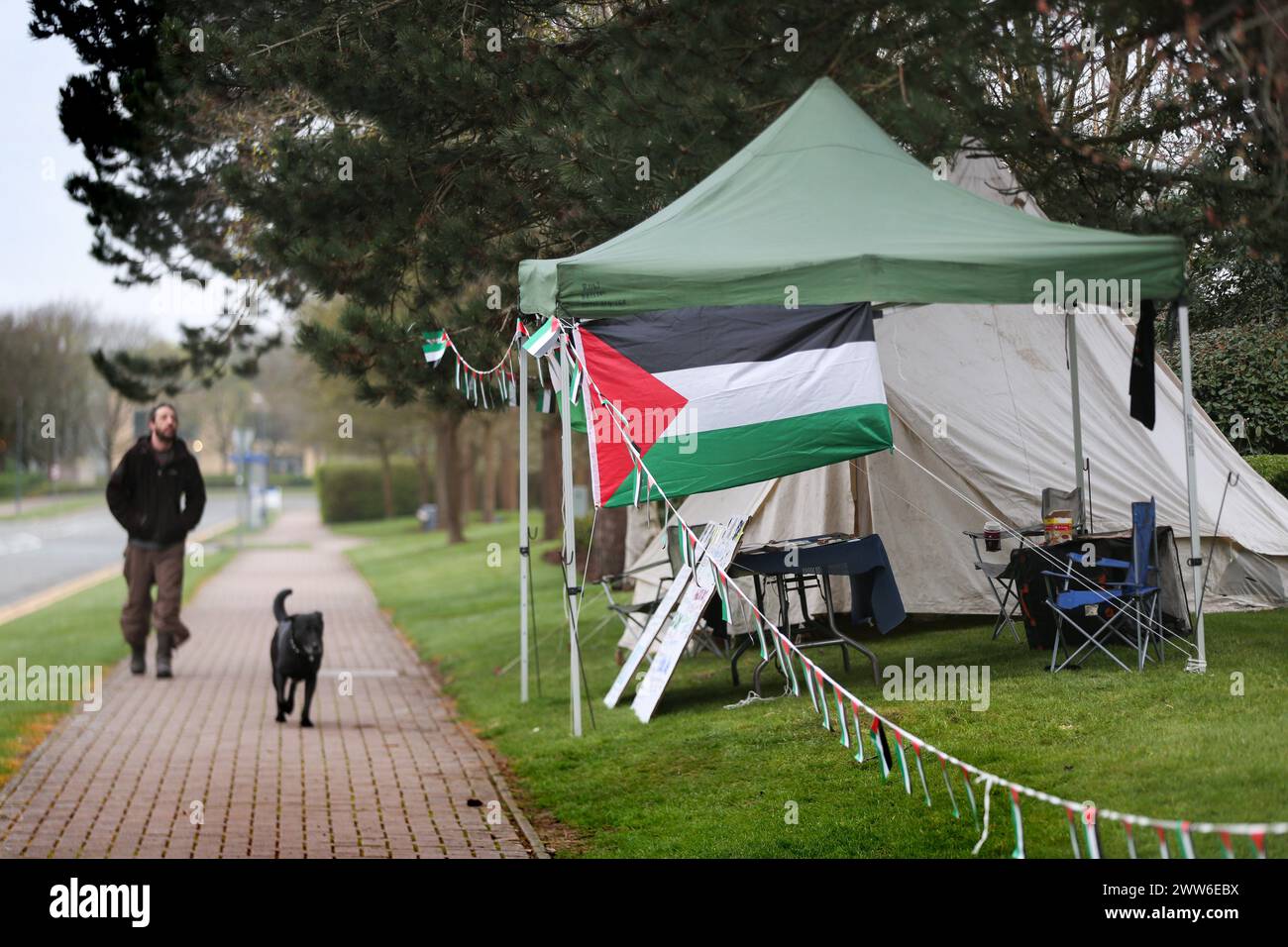 A protester walks with his dog past the roadside camp set up by ...
