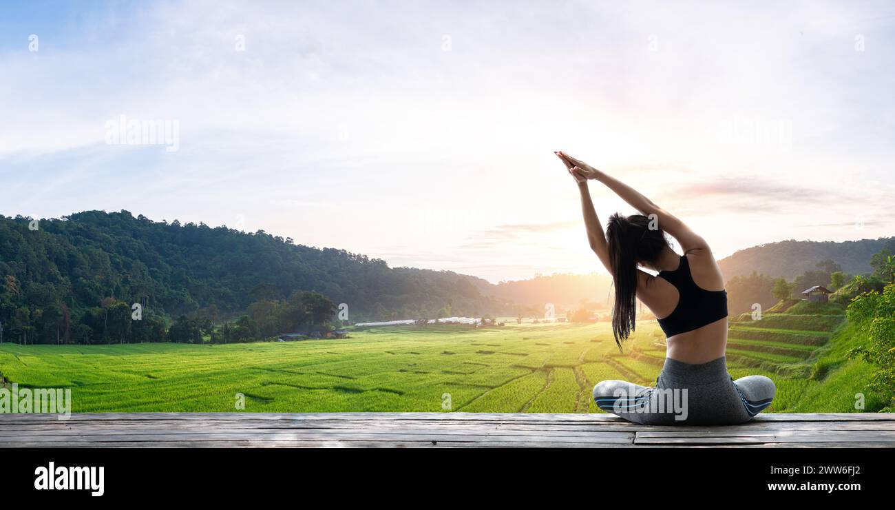 Asian woman doing yoga on the wooden balcony at the rice field in the ...