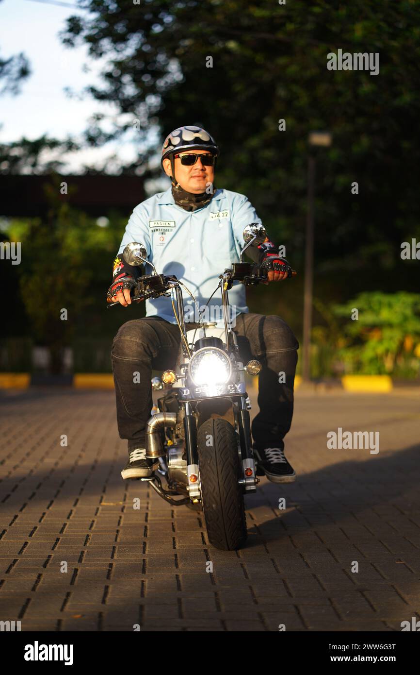 a man riding a mini motorbike with half face helmet Stock Photo - Alamy